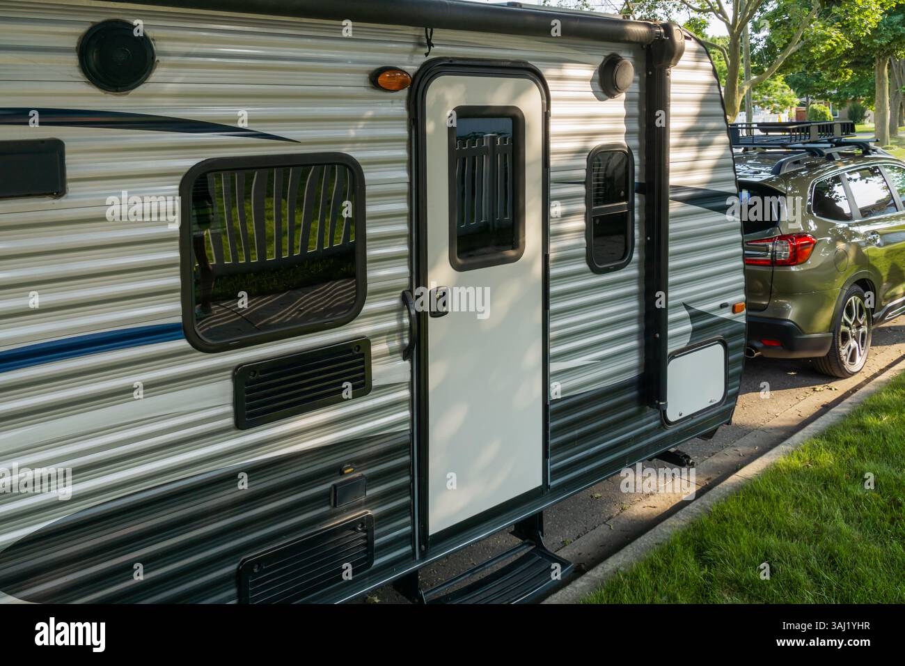 Camping trailer coupled to car parked on the road by a sidewalk Stock ...