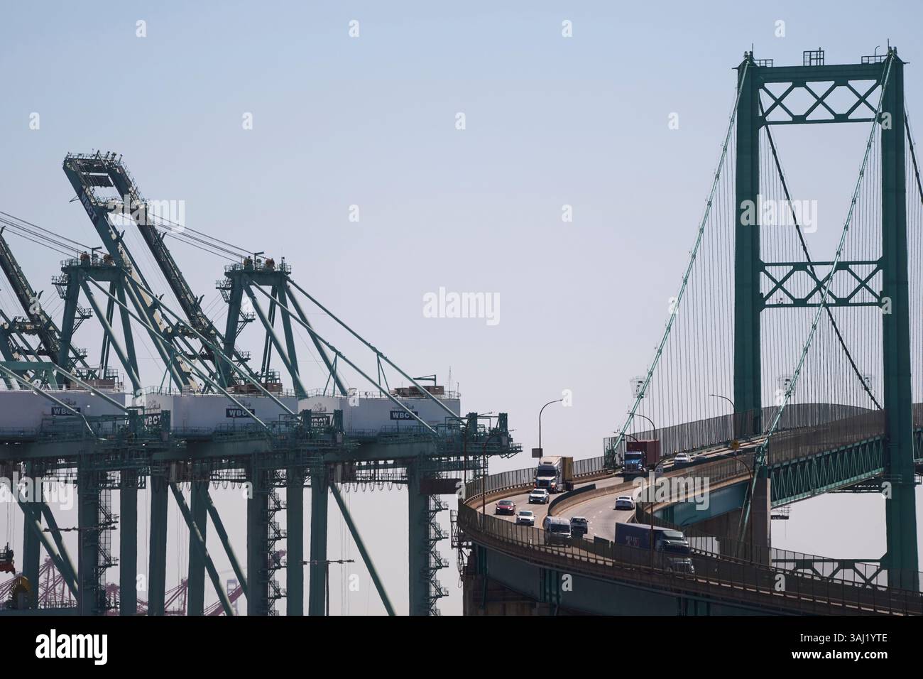 Vehicles cross the Vincent Thomas Bridge past towering cranes at the ...