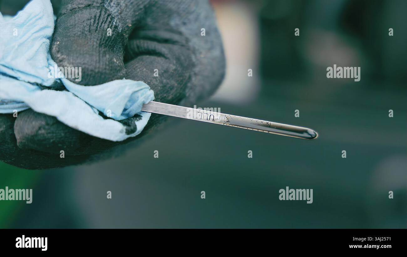 Checking Oil Level with Dipstick. A close-up view of a gloved hand ...