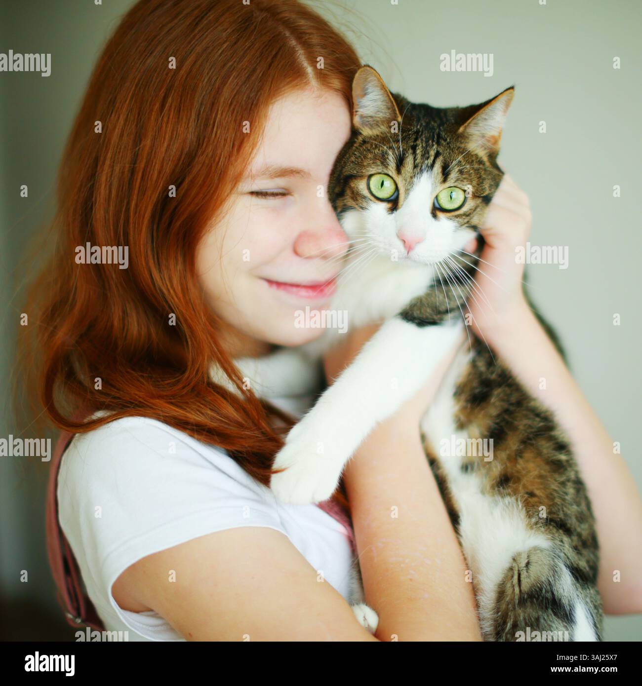 Teen girl with long red hair holding adorable cat close, showing ...