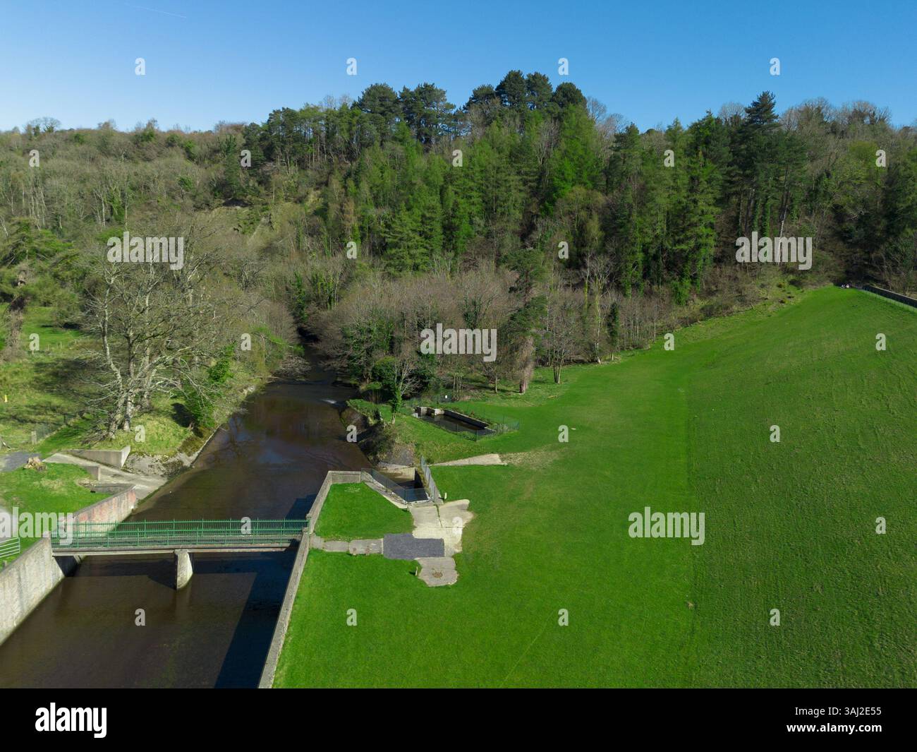 A high-angle aerial shot shows a dam with water flowing through it, a ...