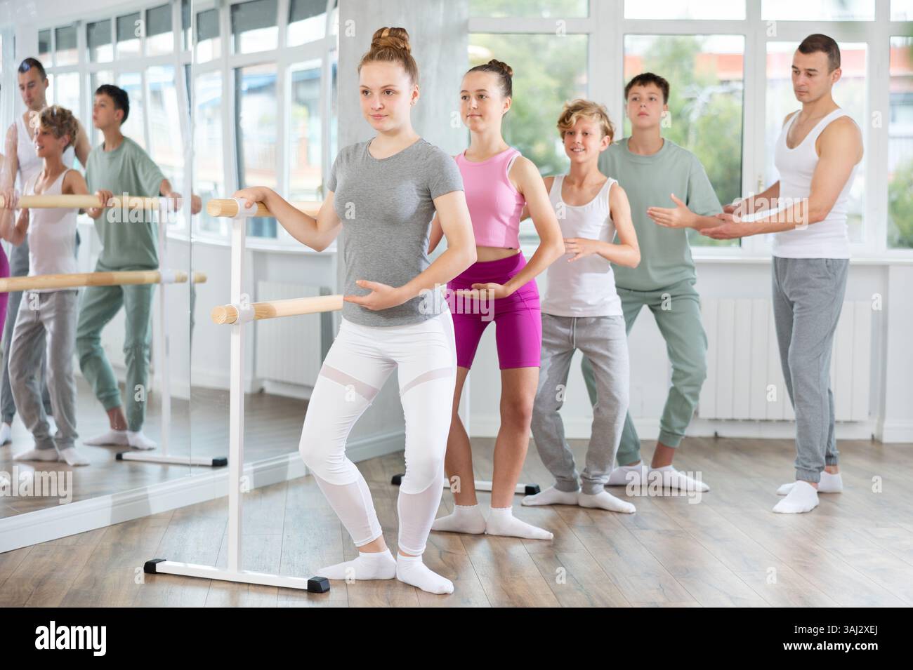 Male teacher conducts class with teens in ballet studio, observes doing ...