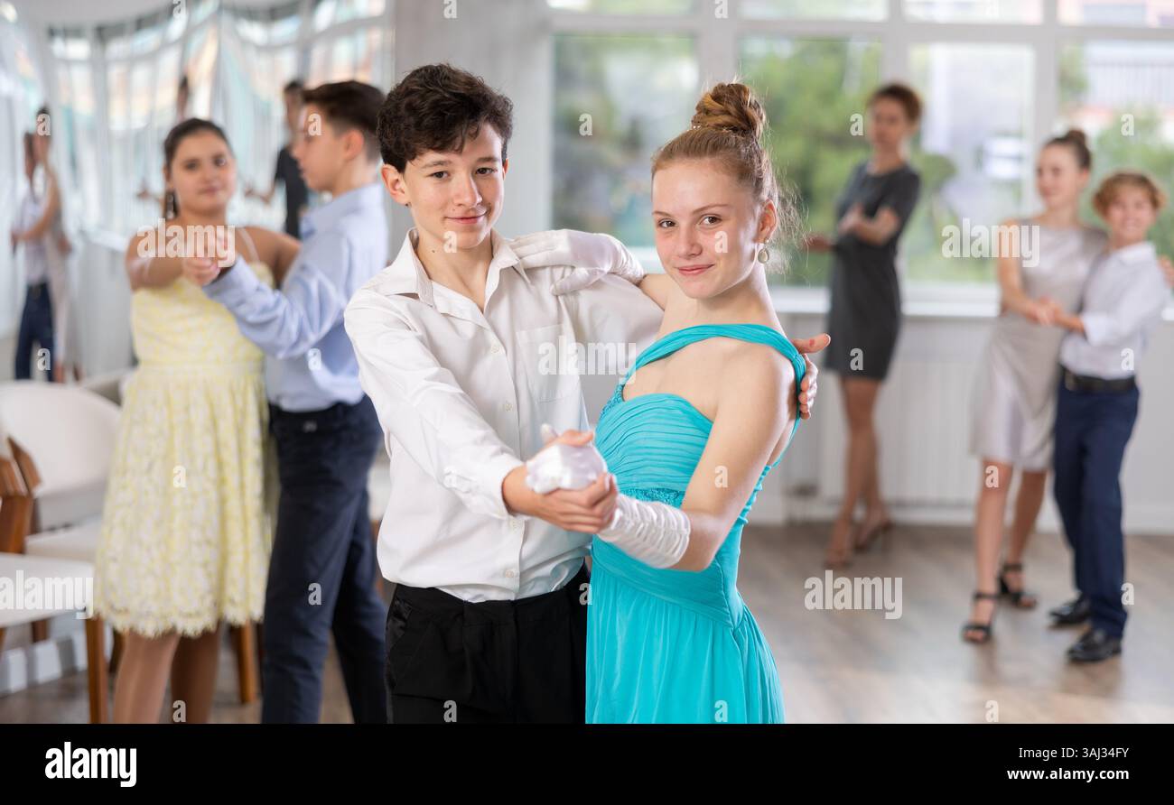 Positive teen boy and girl are dancing classic version of waltz in ...