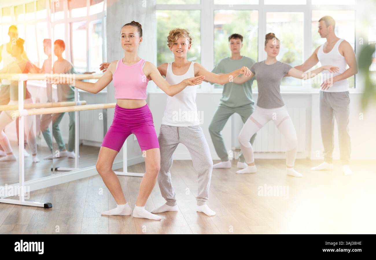 Teenage girl and boy practicing plie position of ballet in dance studio ...
