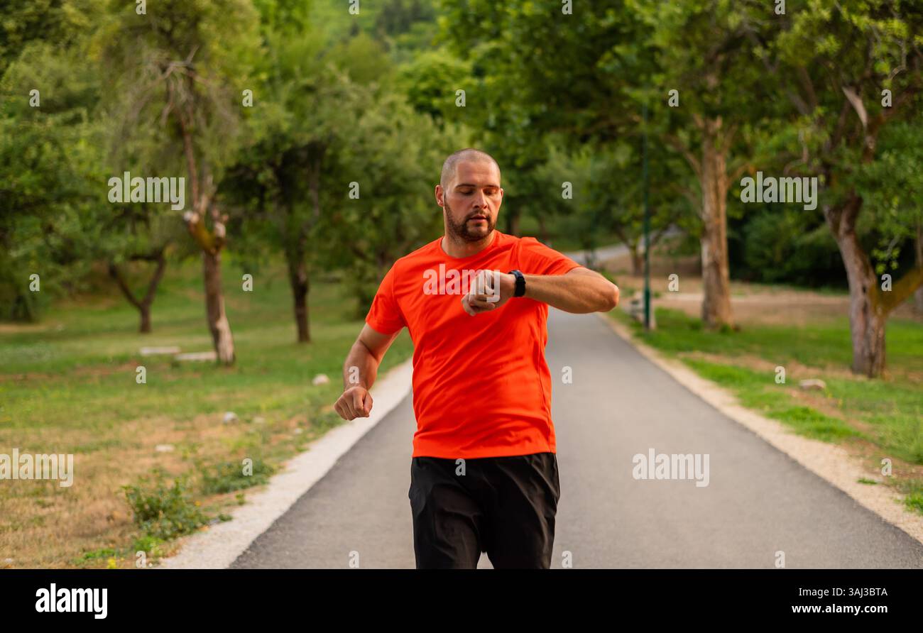 Sporty man looking at a monitor watch checking heart rate while running ...