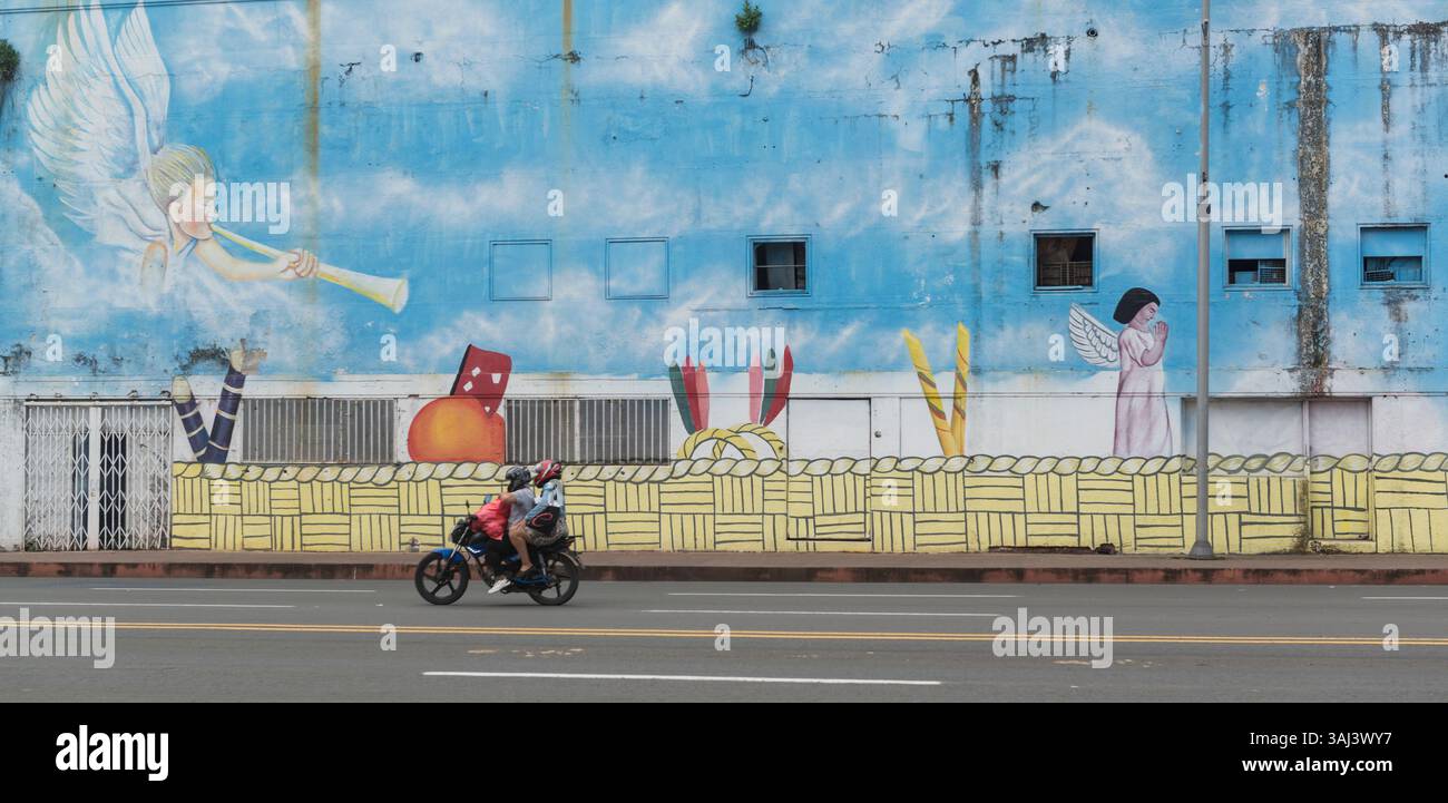 Passing motorcycle in front of a mural covered wall of the Iglesia de ...