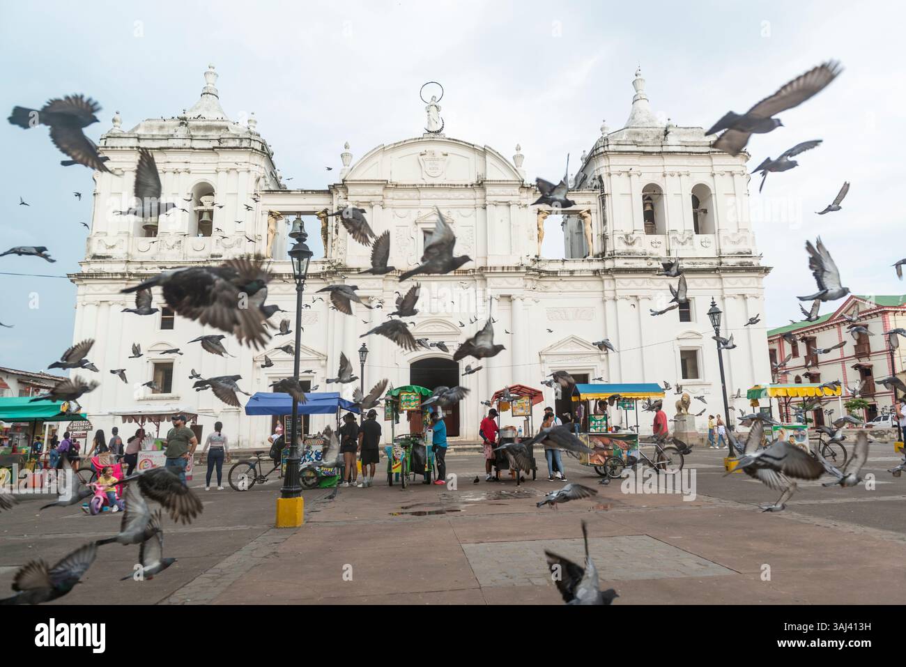Street vendors, flying pigeons and people in front of Leon Cathedral ...