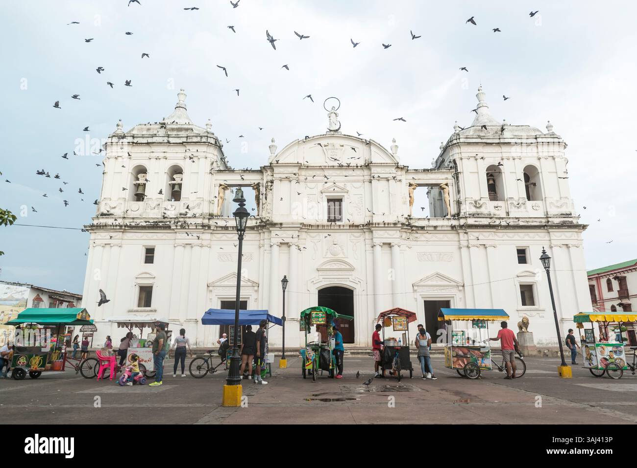 Street vendors, flying pigeons and people in front of Leon Cathedral ...