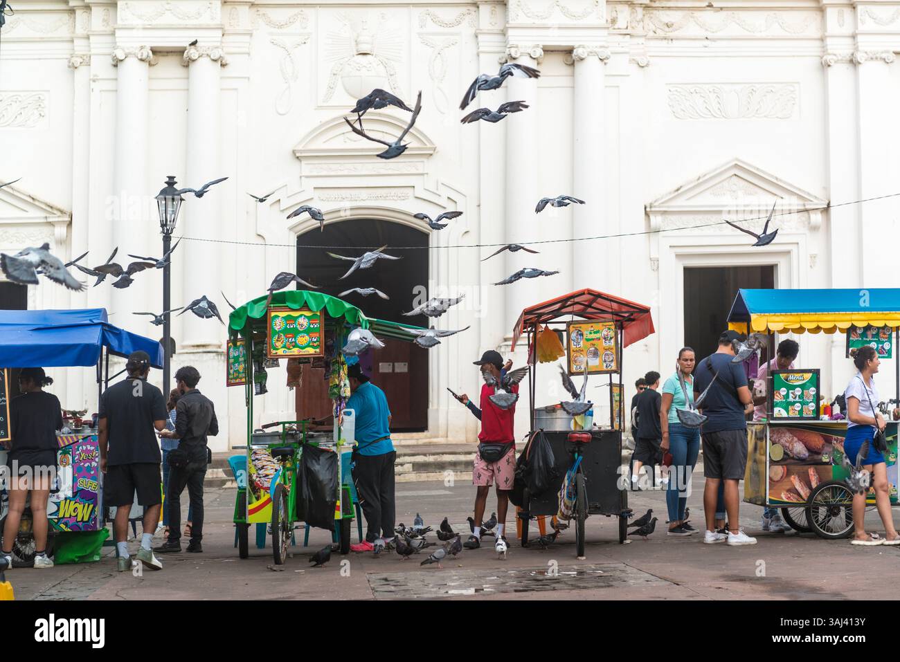 Street vendors, flying pigeons and people in front of Leon Cathedral ...