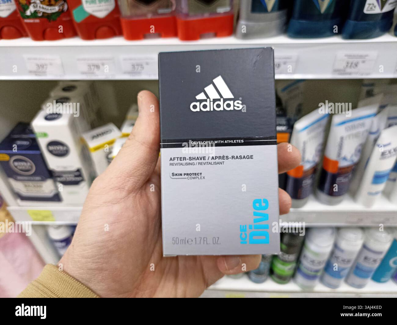 Male hand holding adidas ice dive aftershave in store display Stock ...