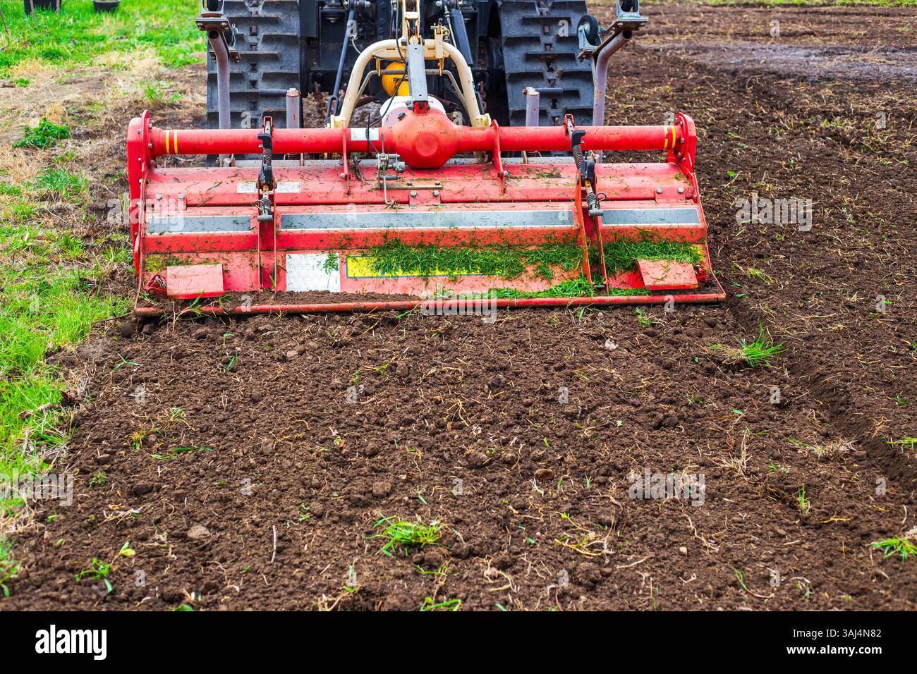 A caterpillar tractor mills the soil in a rural field, a close-up of ...