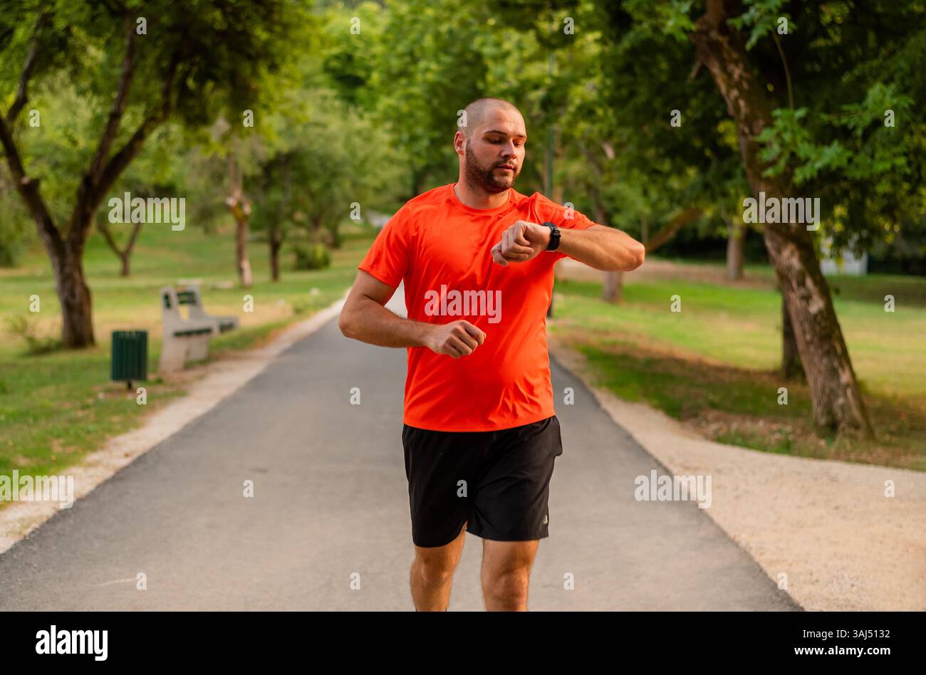 Sporty man looking at a monitor watch checking heart rate while running ...