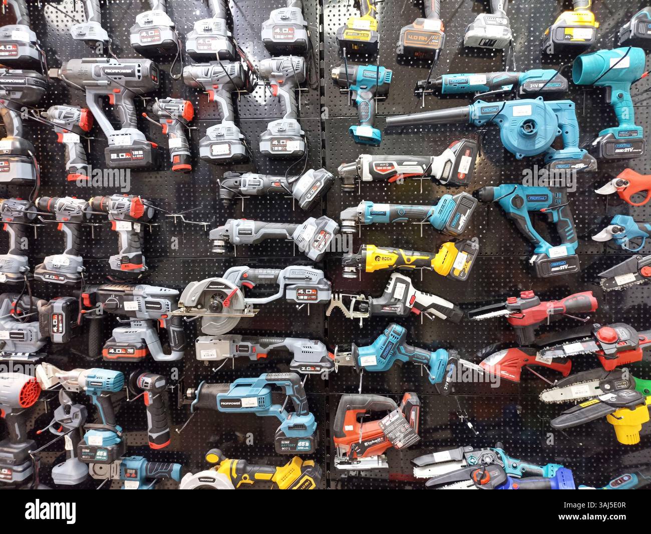 Diverse array of power tools displayed on black pegboard wall in ...