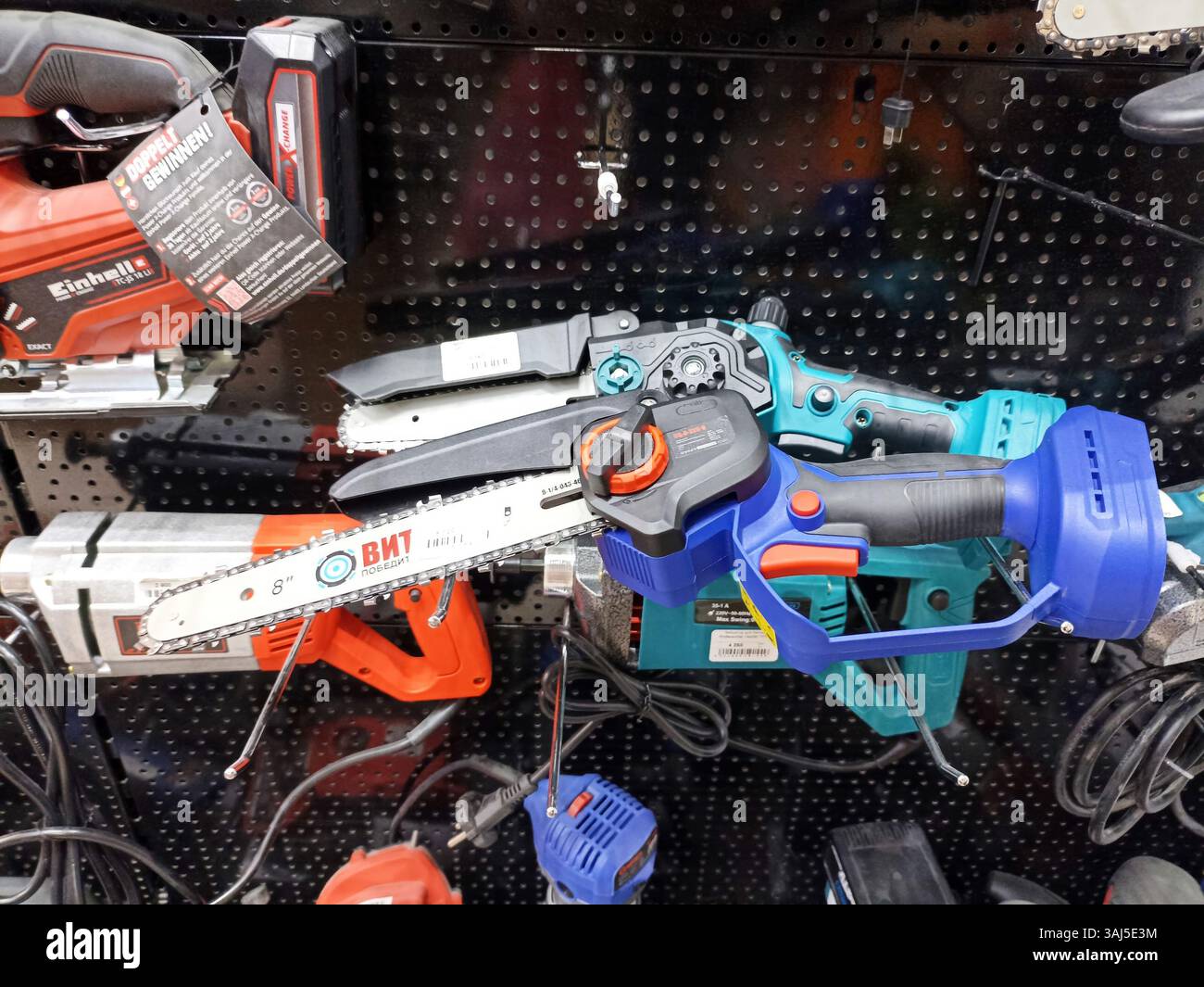 Electric chainsaws display in hardware store on black pegboard wall ...