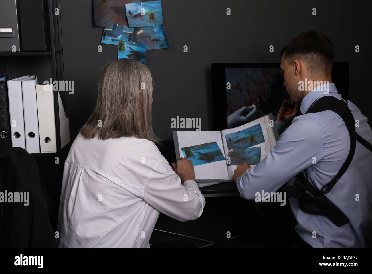 Forensic experts working with crime scene photos in office, back view ...
