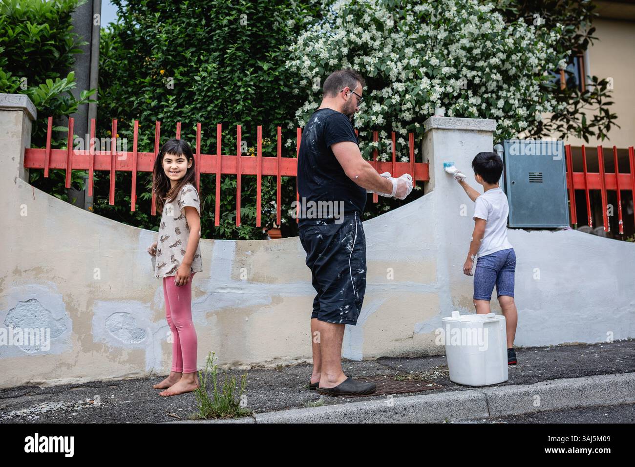 dad with two daughters painting in white the old house fence Stock ...
