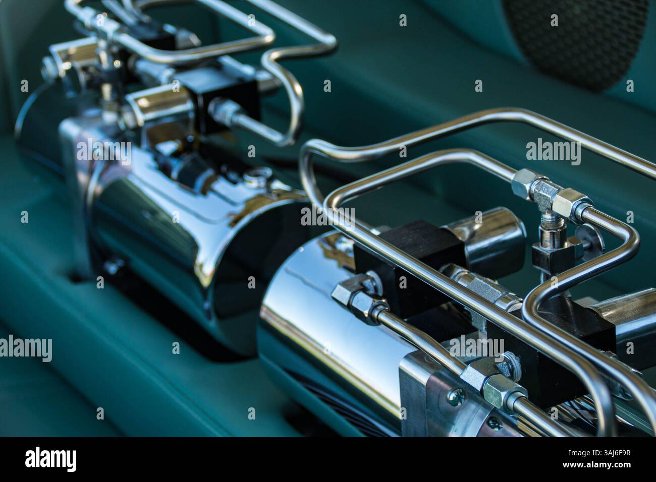 A pair of chrome hydraulic tanks and tubing mounted in the trunk of a ...
