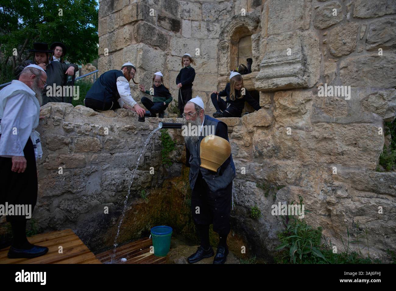 Ultra-Orthodox Jewish men gather to collect water from a spring to make ...
