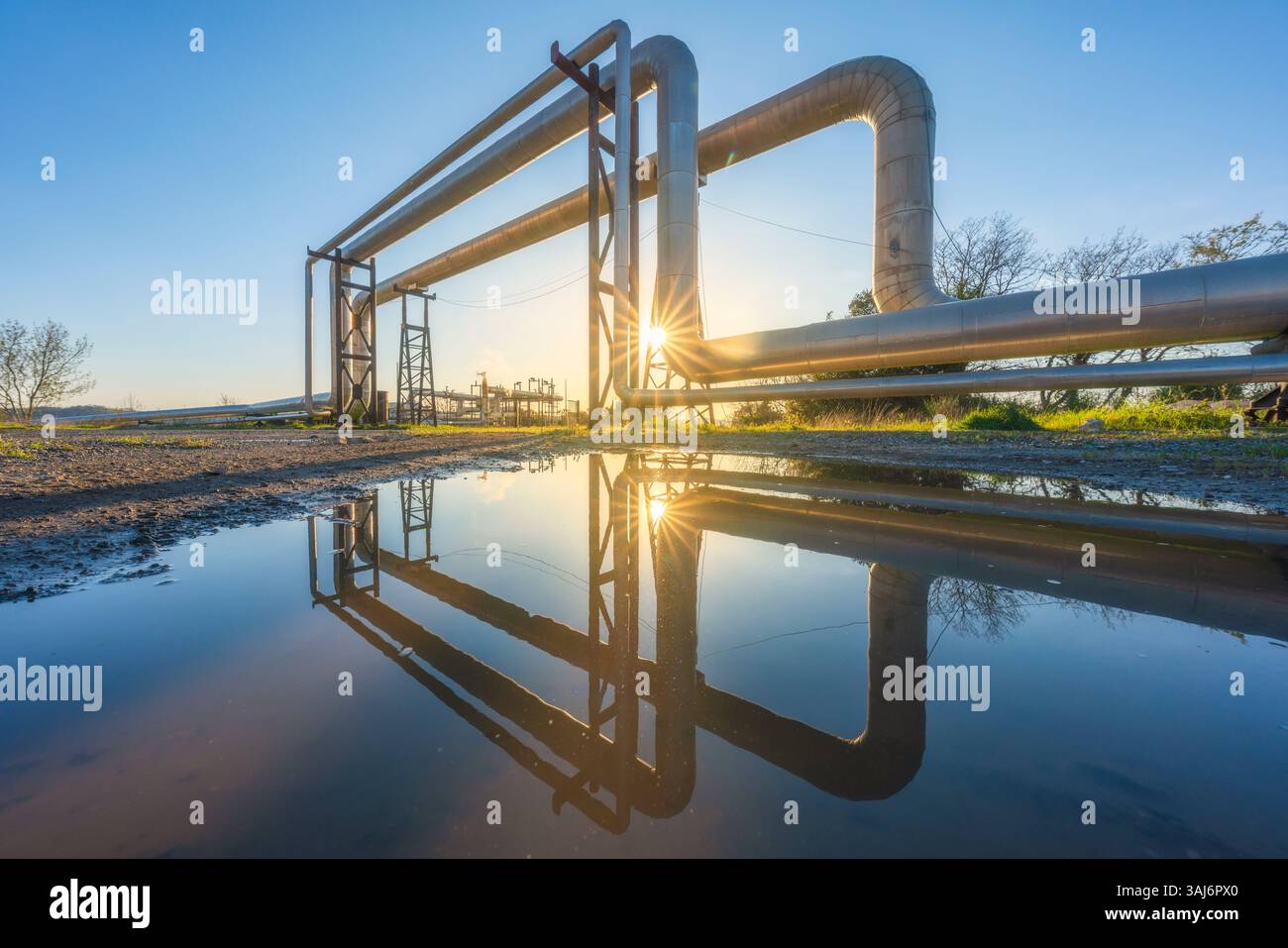 Pipelines of a geothermal power plant and reflection in the water at ...