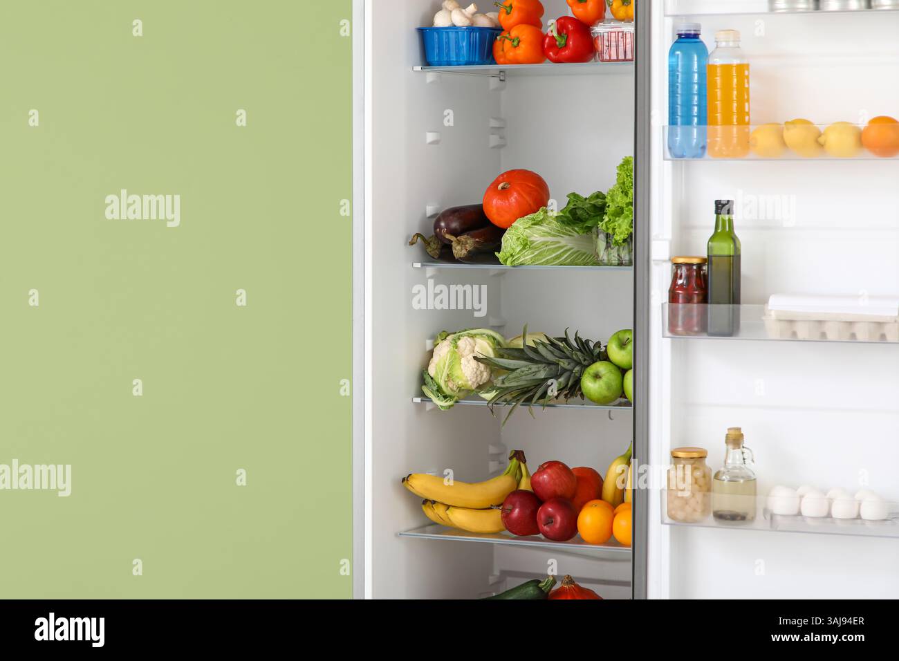 Open fridge full of fresh food near green wall Stock Photo - Alamy