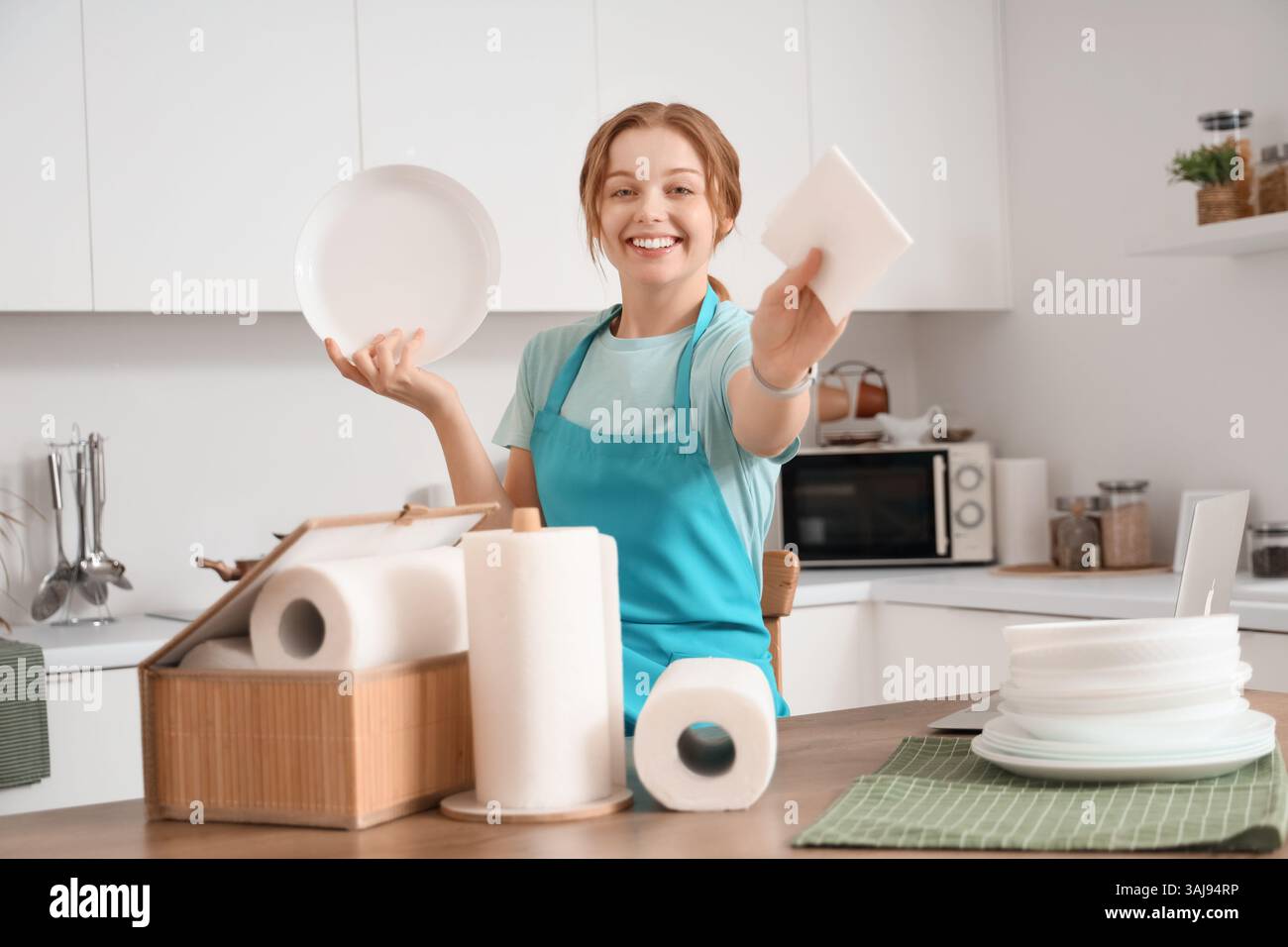 Young woman with paper napkins and plate in kitchen Stock Photo - Alamy