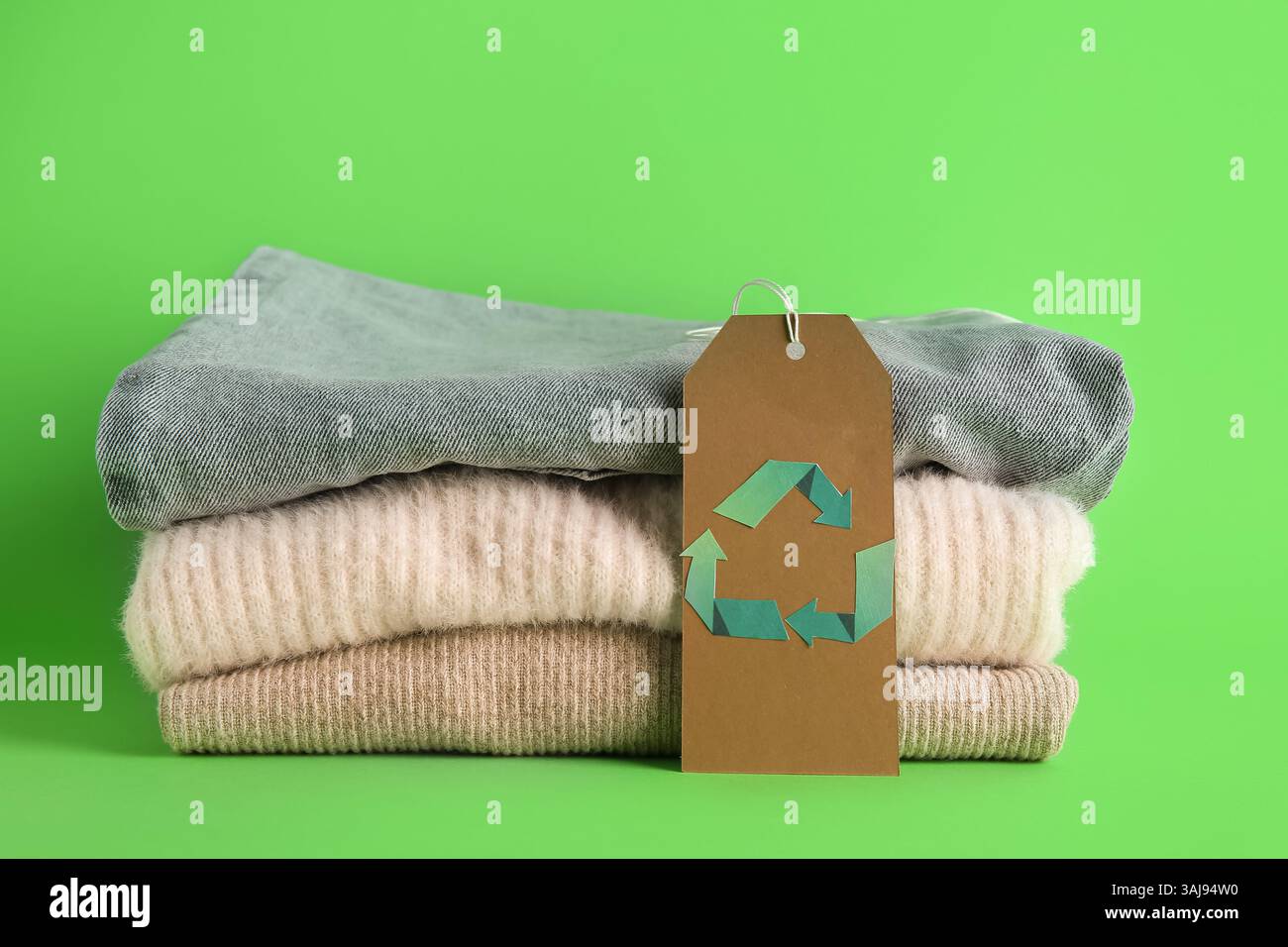 Stack of clothes with recycling tag on green background Stock Photo - Alamy