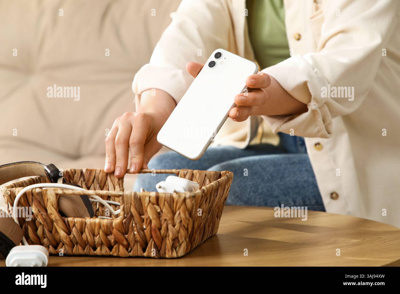 Young woman putting mobile phone into basket at home, closeup. National ...