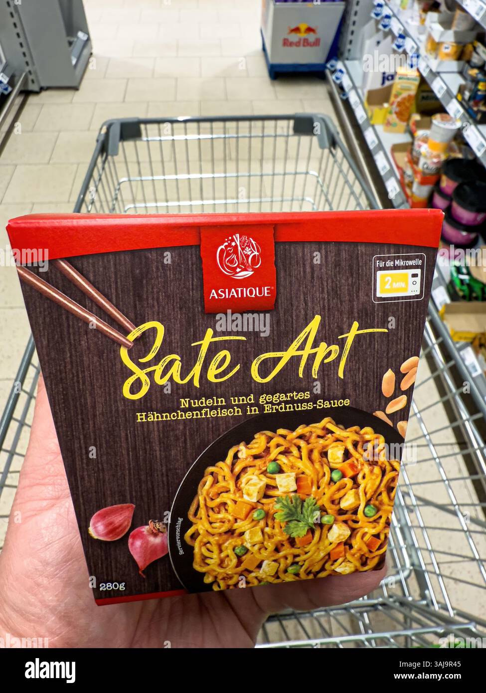 Hand holding a package of sate art instant noodles with chicken and ...
