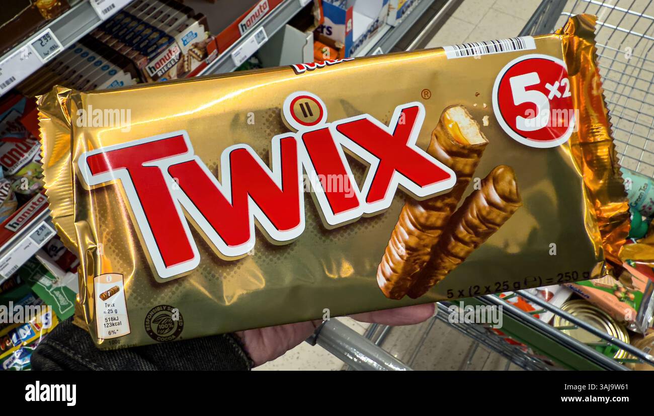 Hand holding a gold package of twix chocolate bars in a supermarket ...