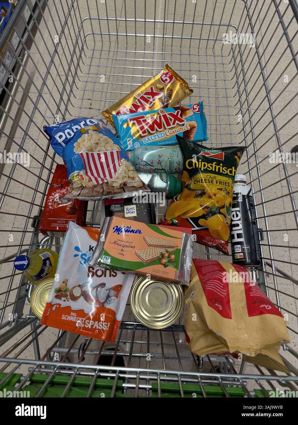 Metal shopping cart filled with various snacks and drinks, including ...