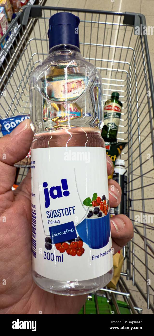 Hand holding a bottle of ja. Liquid sweetener in a shopping cart at the ...