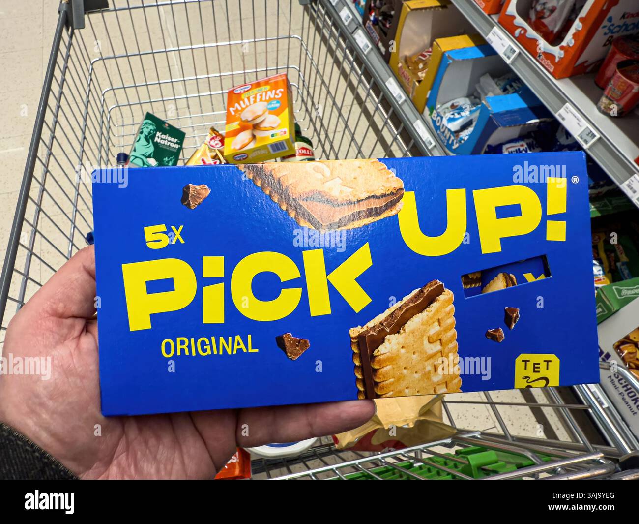 Hand holding a package of pick up. Original biscuits in a supermarket ...