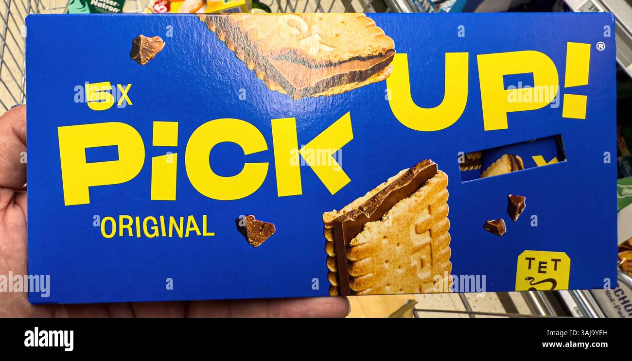 Hand holding a blue box of pick up. Original chocolate biscuits in a ...