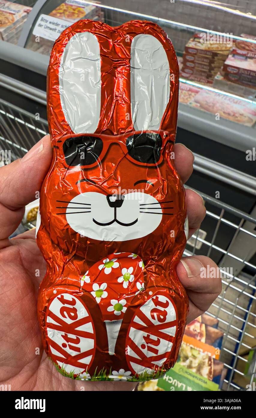 Customer choosing a red foil wrapped KitKat chocolate easter bunny with ...