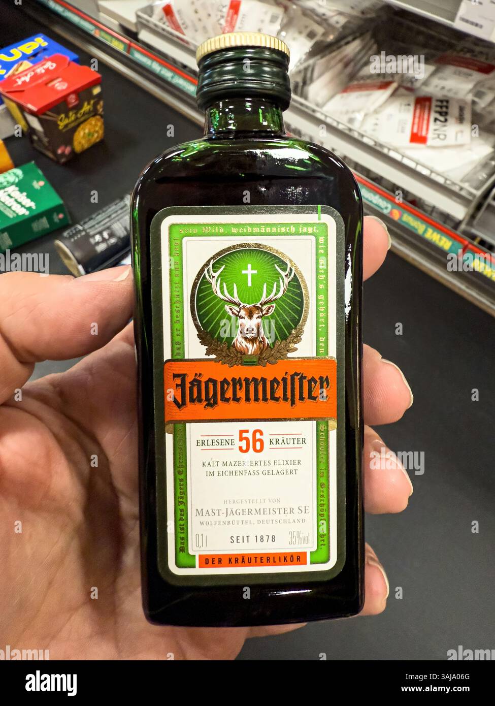 Hand holding a small bottle of jagermeister digestif in a supermarket ...