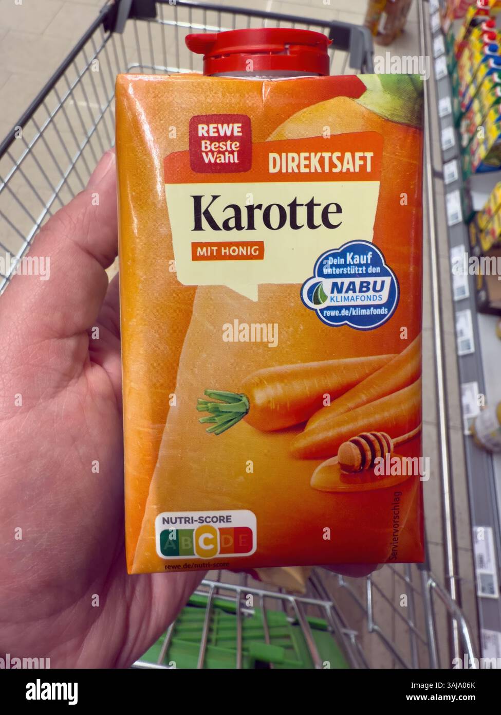Hand holding a carton of rewe beste wahl carrot juice with honey ...