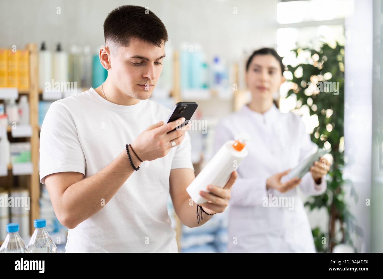 Young male customer buying and scanning qr code for gel in pharmacy ...