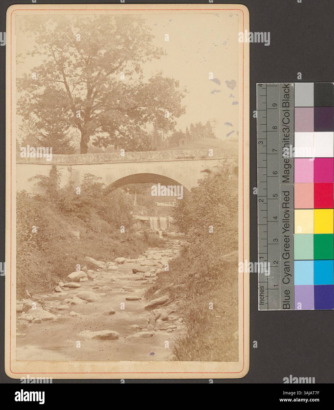 This photograph shows a bridge over a stream, possibly the ...