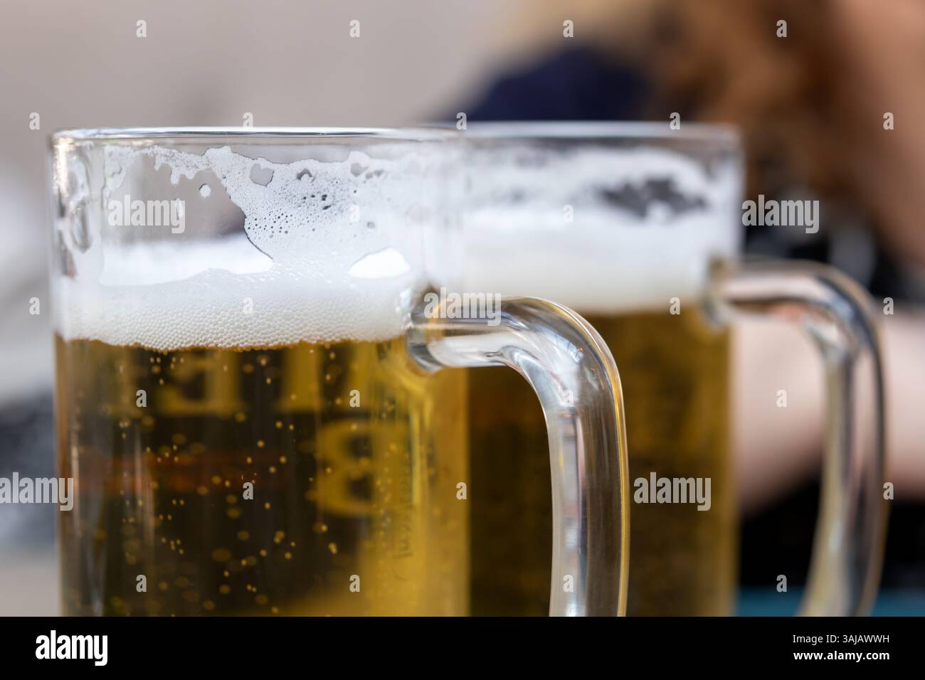 Two frothy beer mugs in a bar Stock Photo - Alamy