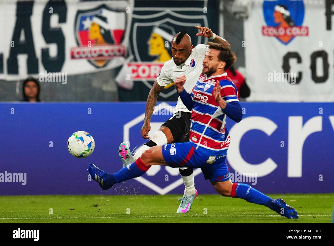 Arturo Vidal of Chile's Colo Colo, back, connects a shot challenged by ...