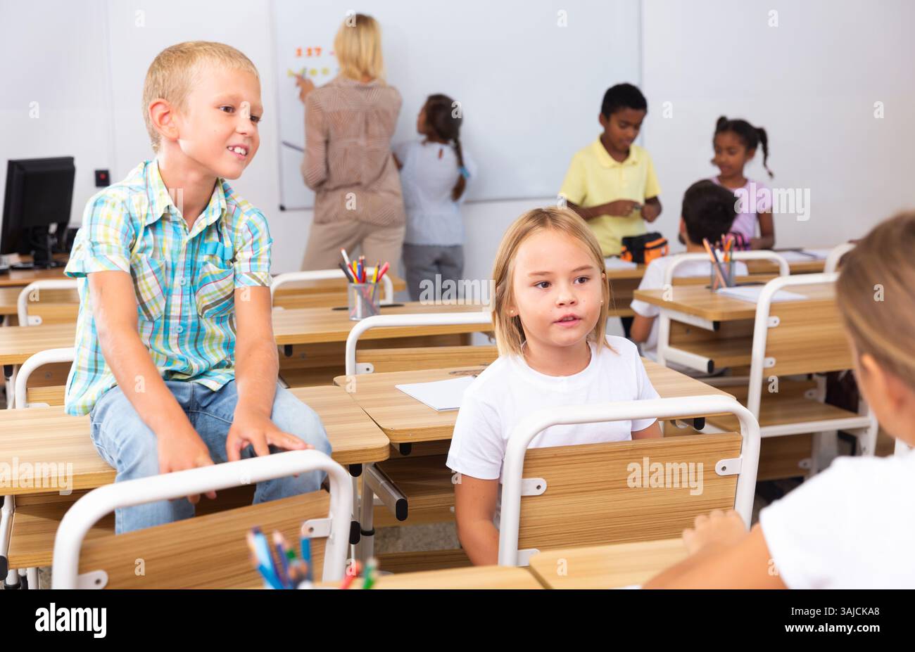 Cheerful preteen classmates talking at recess between lessons Stock ...