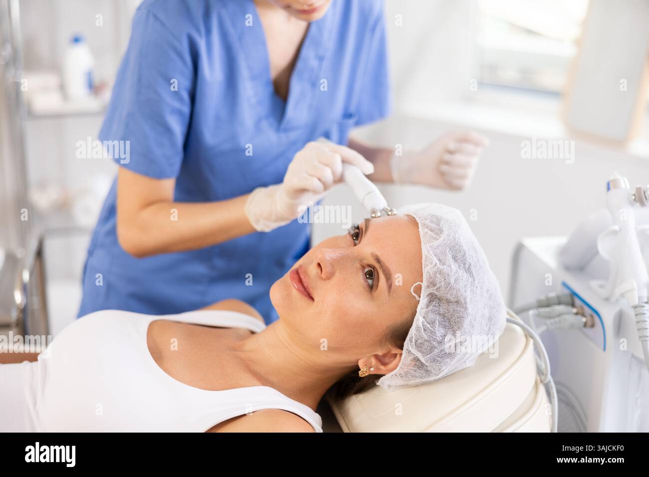 Young woman receiving cosmetic facial radiofrequency facial procedure ...