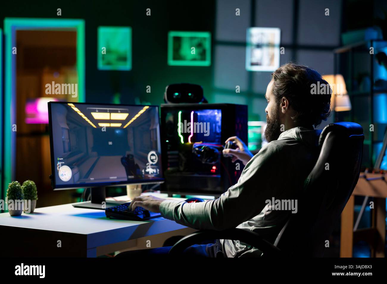 Man in dark living room playing videogame on gaming PC at computer desk ...