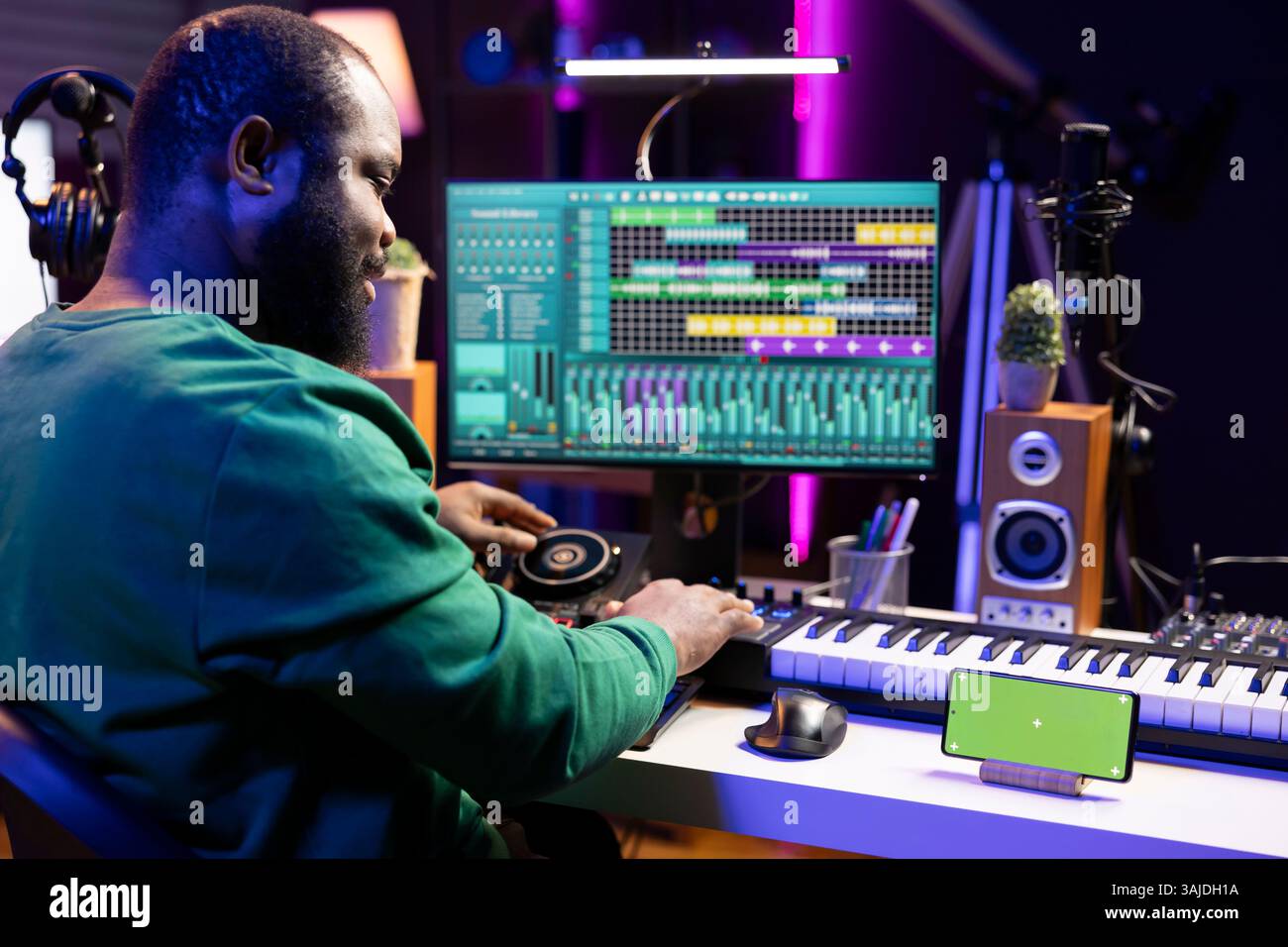 Male composer using mixing console and piano to edit tracks, having a ...