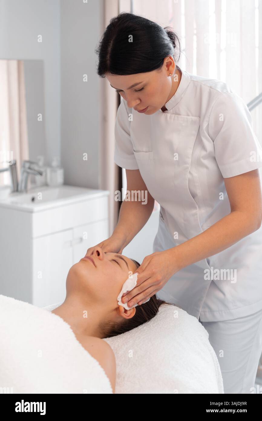 Cosmetologist wiping woman face with antibacterial napkins. Doctor ...