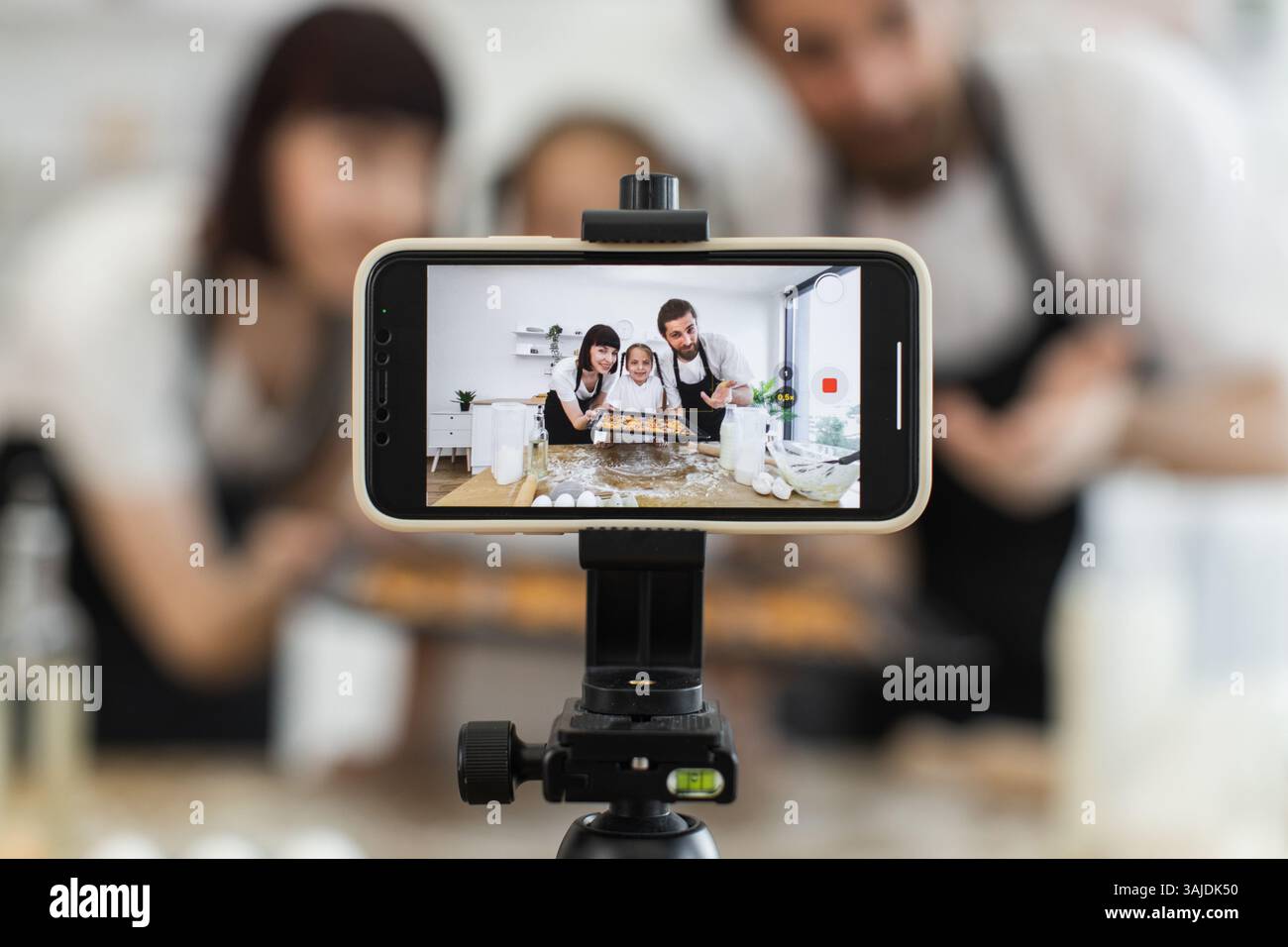 Happy family filming cooking vlog together in kitchen with homemade ...