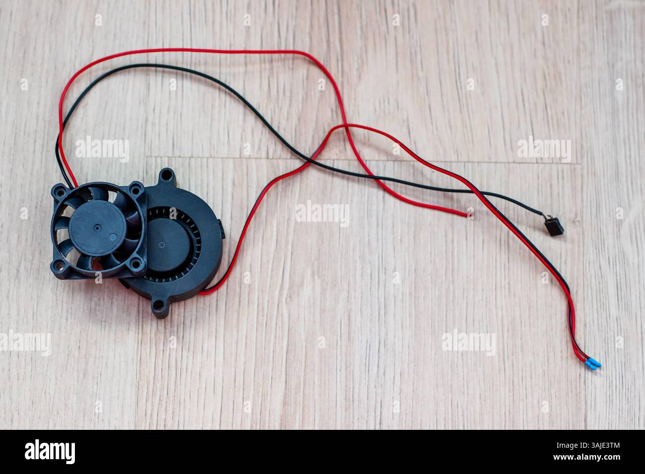 A compact fan featuring red and black wires that are securely attached ...