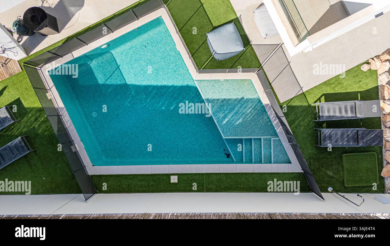 Aerial view of a small private pool with sun loungers and grass area ...