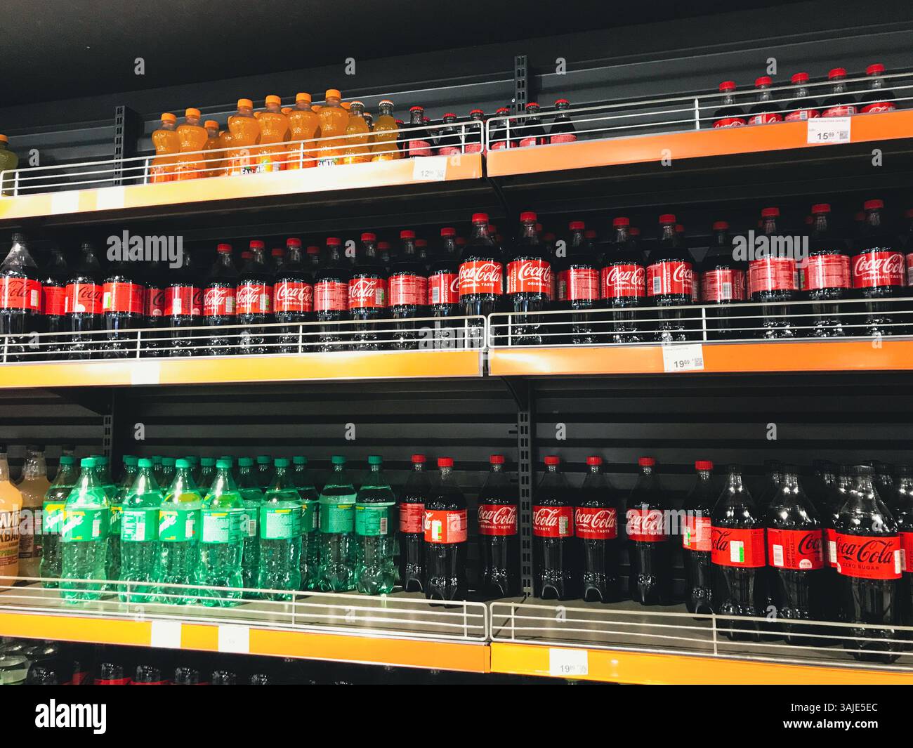 Row of shelves with many bottles of Coca-Cola. The bottles are in ...