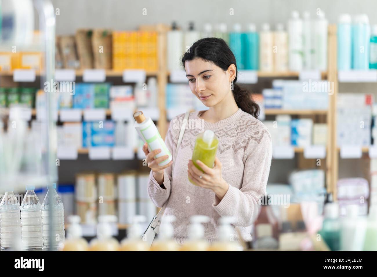 Female shopper in autumn clothes chooses medicated shampoo at pharmacy ...